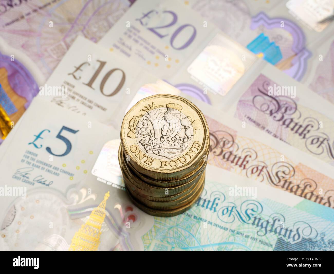 Close up of stack of British pound coins resting on pound notes money ...