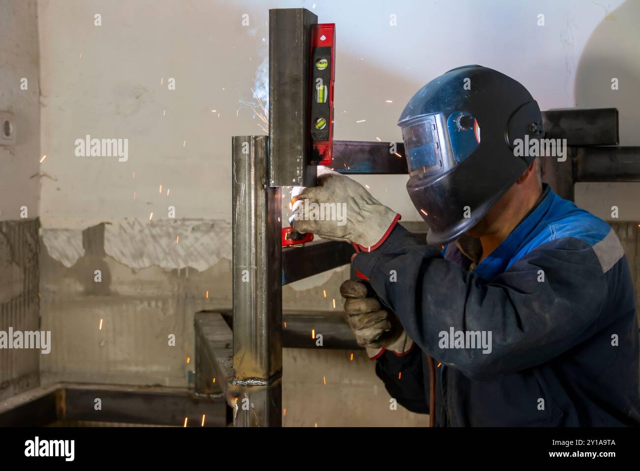 An experienced man using a spirit level and welding a seam on a spiral ...