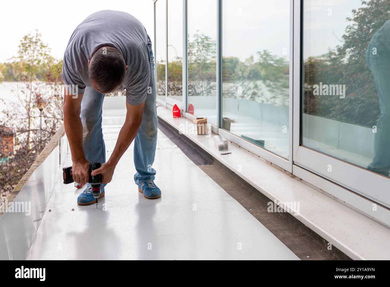 Construction worker installing new metal sheet roof. Man with cordless ...
