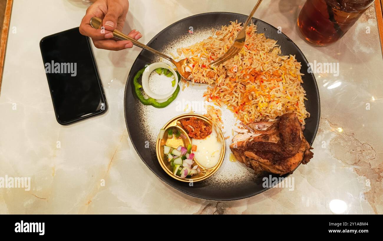 Asian woman's hand is scooping rice with a spoon and fork on a plate of ...