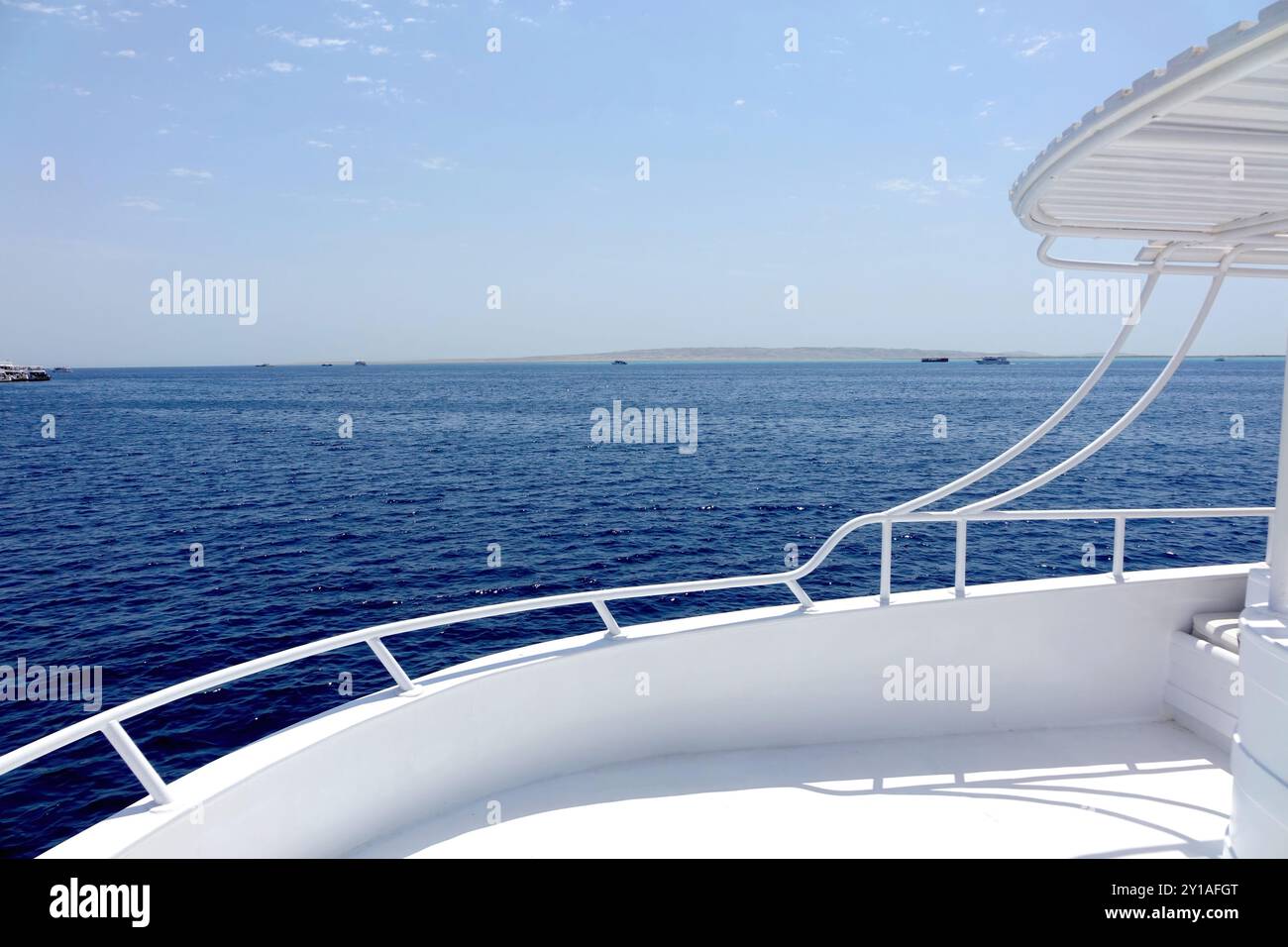 A tranquil view from a yacht shows the deep blue waters of the Red Sea, dotted with distant ...