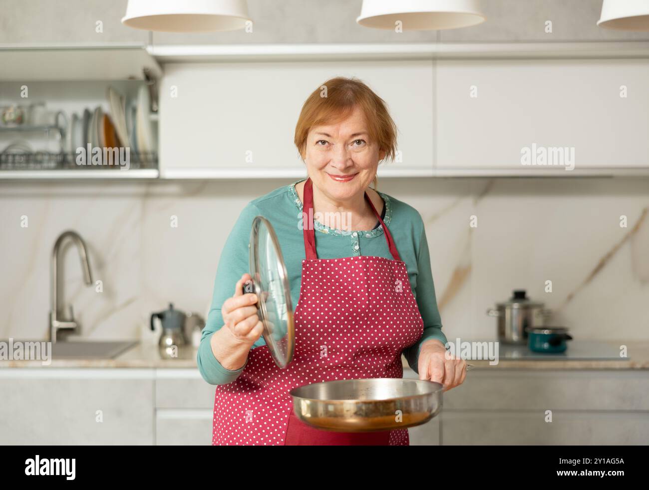 Adult woman in apron posing with frying pan Stock Photo - Alamy