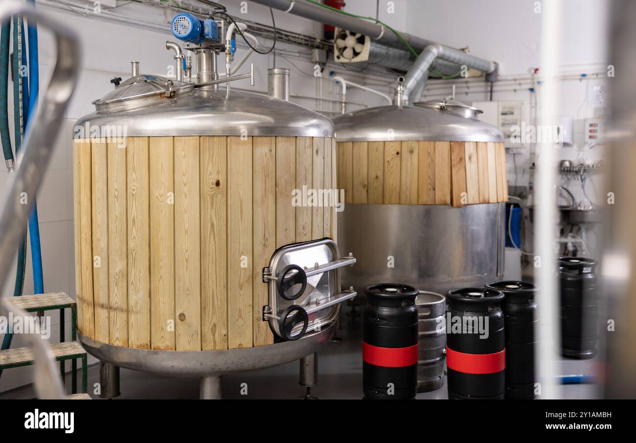 Interior of small brewery with tanks for beer fermentation and kegs ...