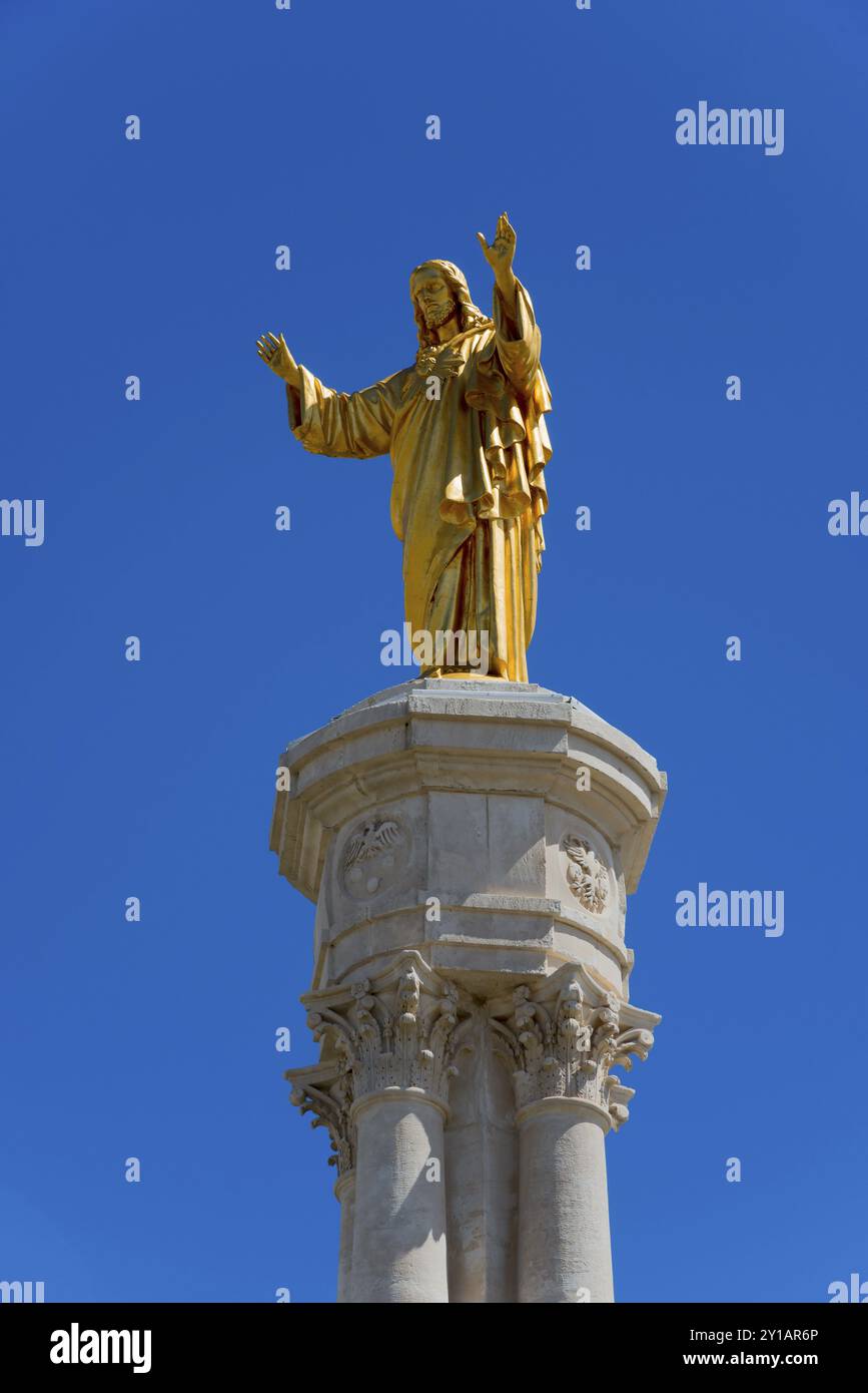 Golden statue of Jesus on a high column in front of a blue sky, Christ ...