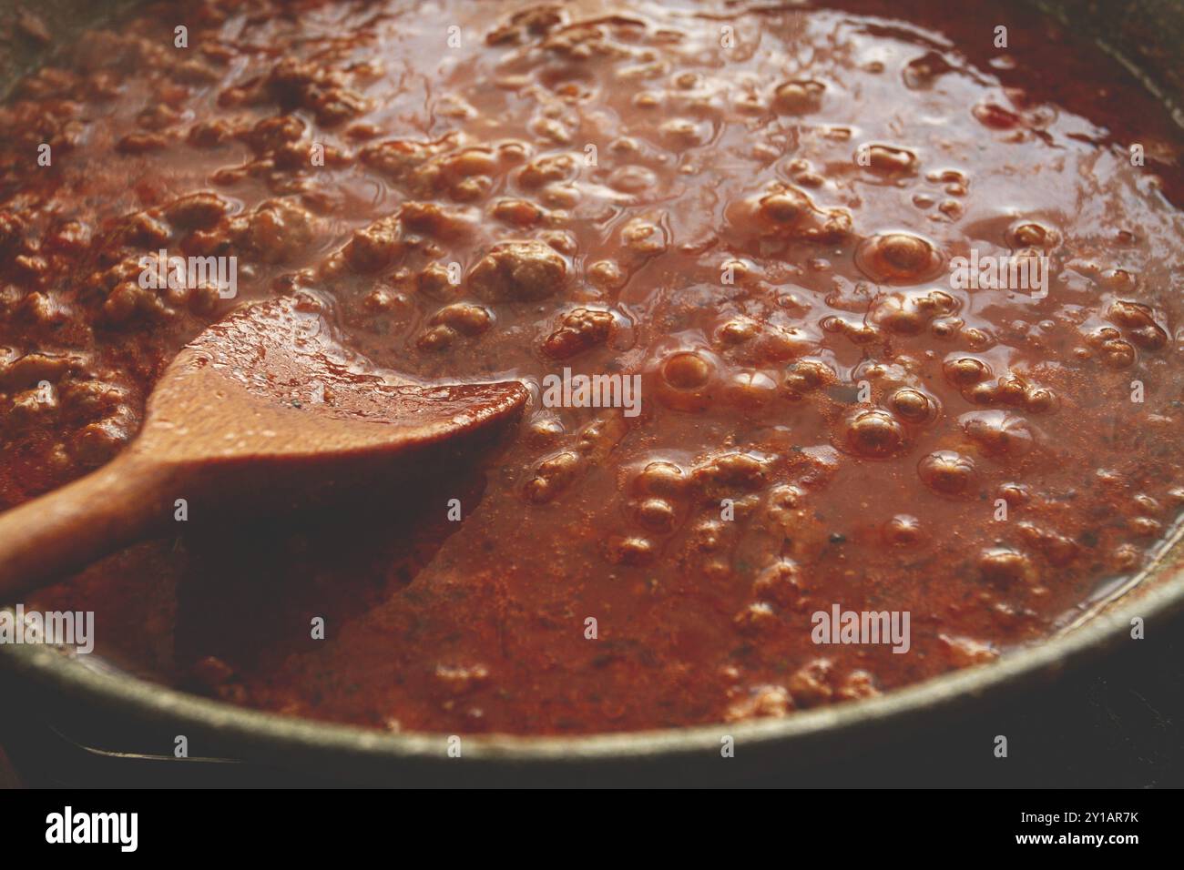 Cooking, bolognese sauce, in a frying pan, stirring with a wooden spoon ...