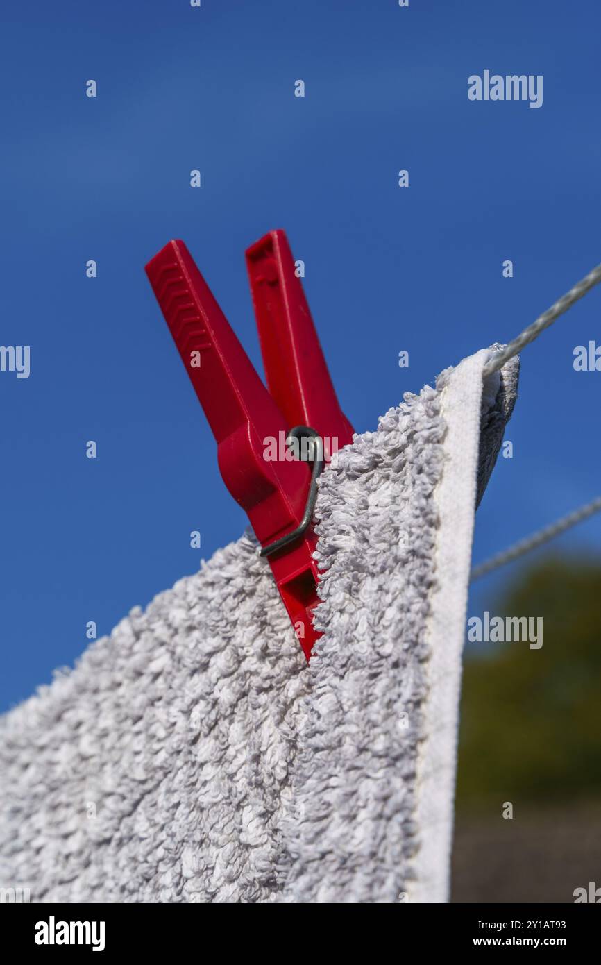 Red clothes peg holding a wet towel on a clothesline, in front of a ...