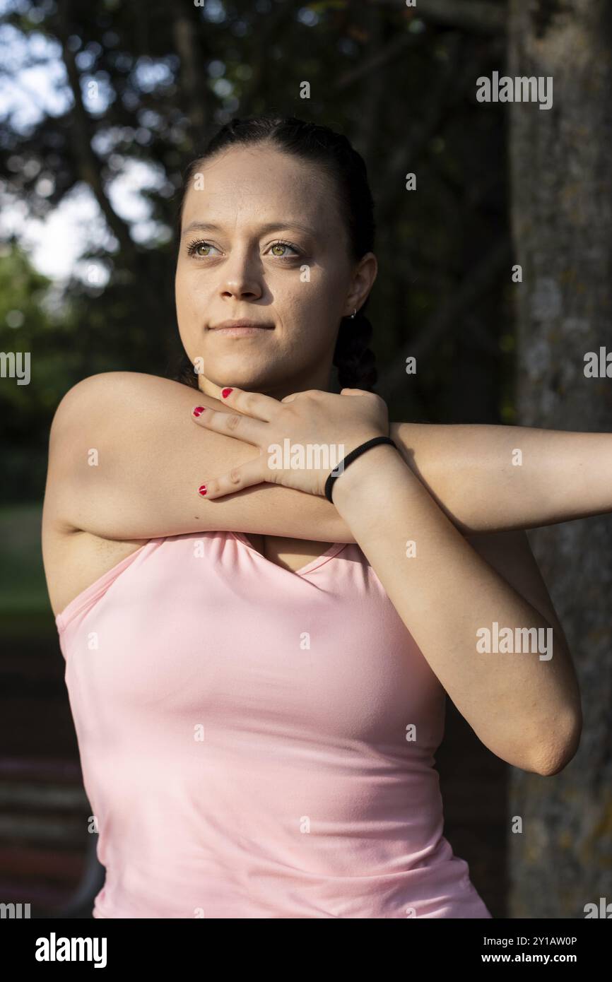 Vertical front view of a confident young woman doing arm stretches ...