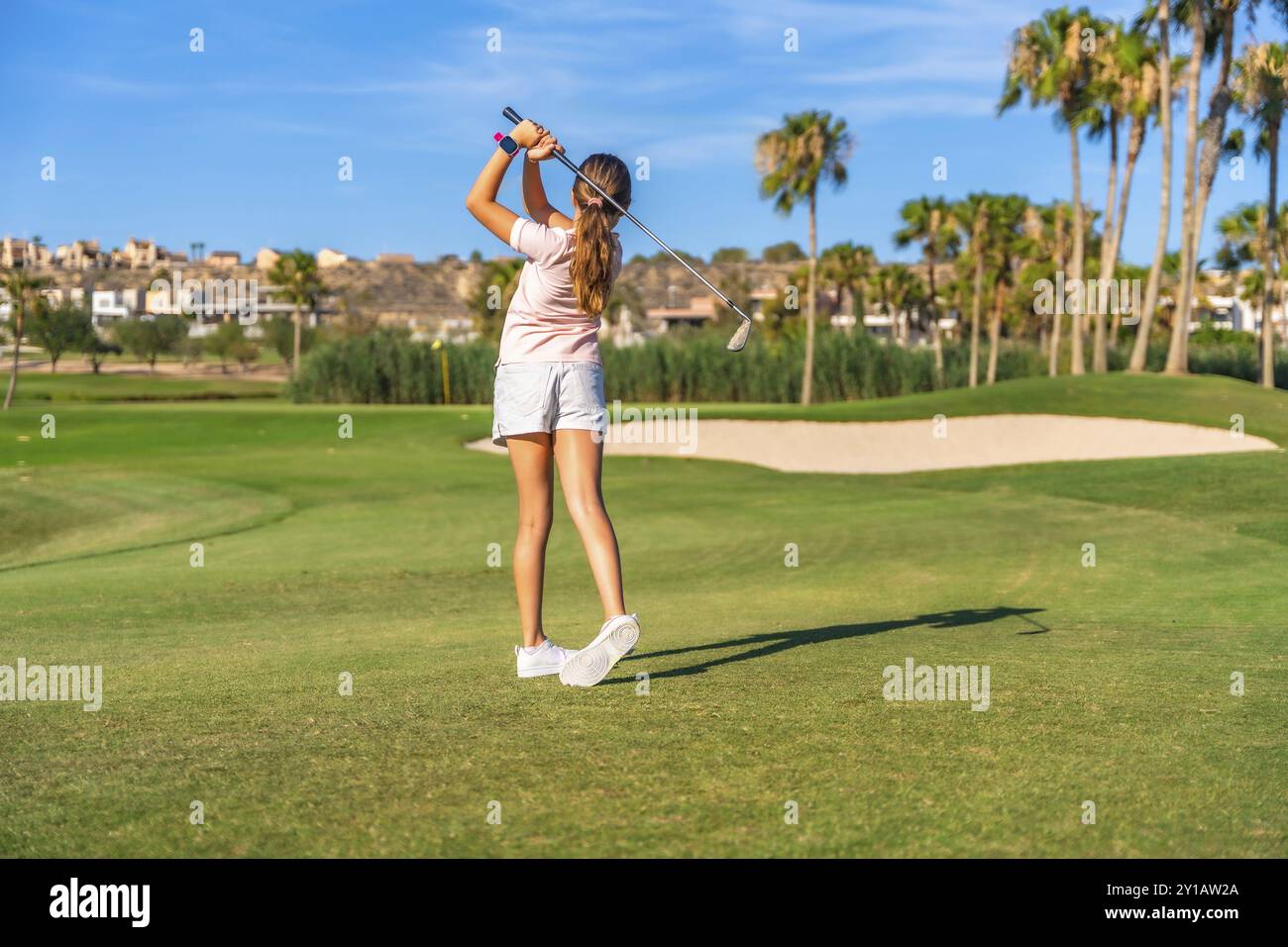 Rear view of a girl swinging golf during golf lessons in summer Stock ...