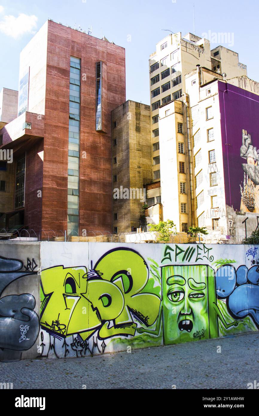 A wall painted by green and blue graffiti surrounds office buildings in ...