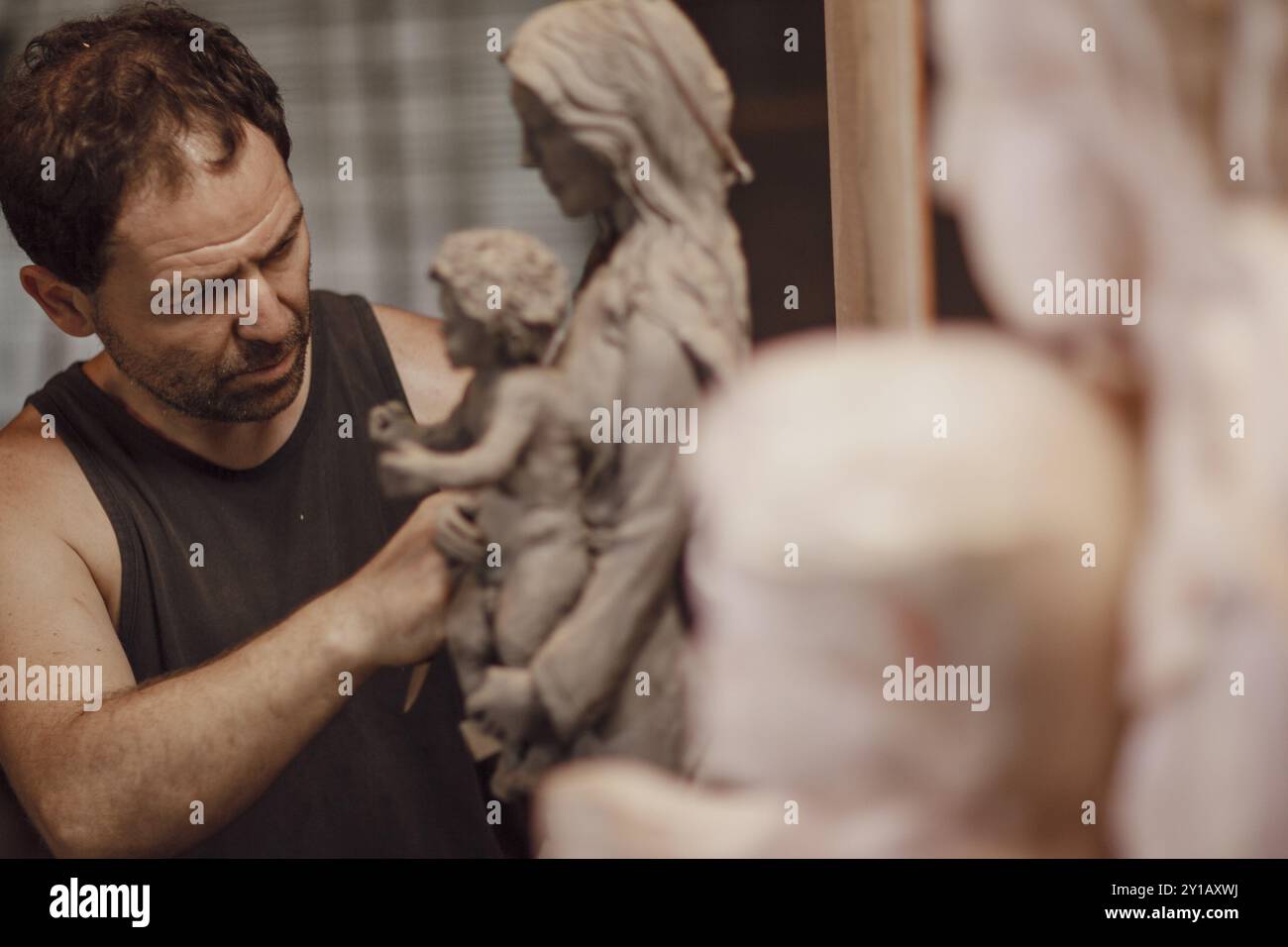Sculptor deeply involved in the intricate detailing of a clay sculpture ...