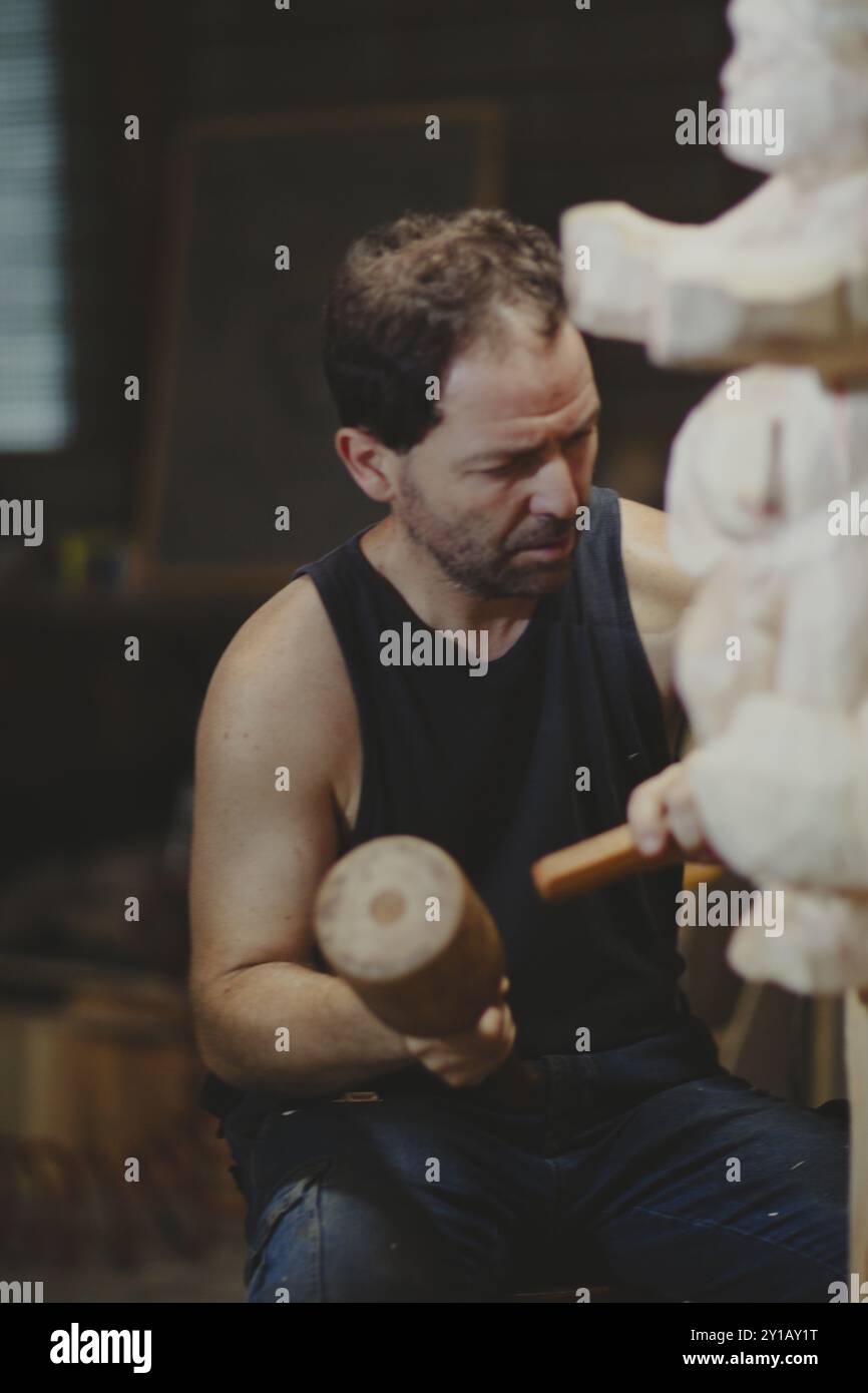 Man engaged in woodcarving with a mallet, demonstrating concentration ...
