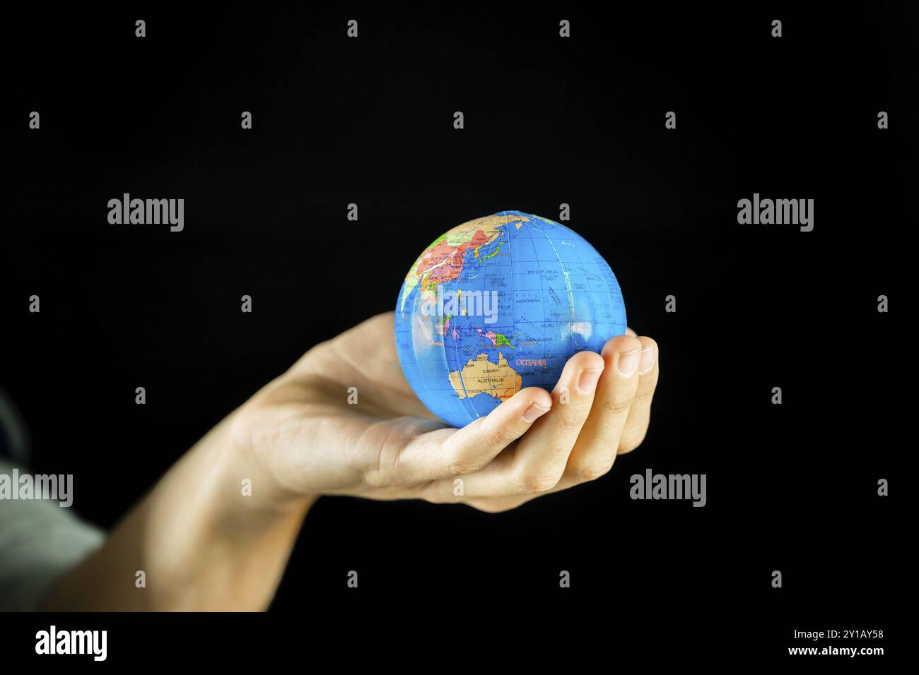 Male hands holding the Earth globe on black background Stock Photo - Alamy
