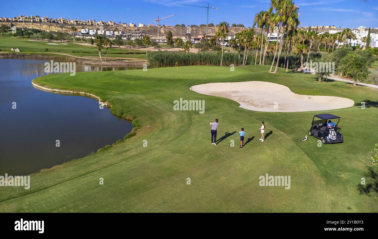 Aerial drone wide view of three people playing in a luxury golf course ...