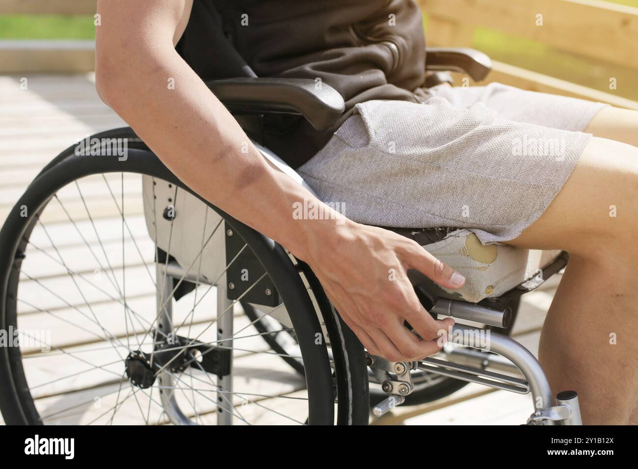 Disabled young athletic man on a wheelchair holding and turning wheels ...