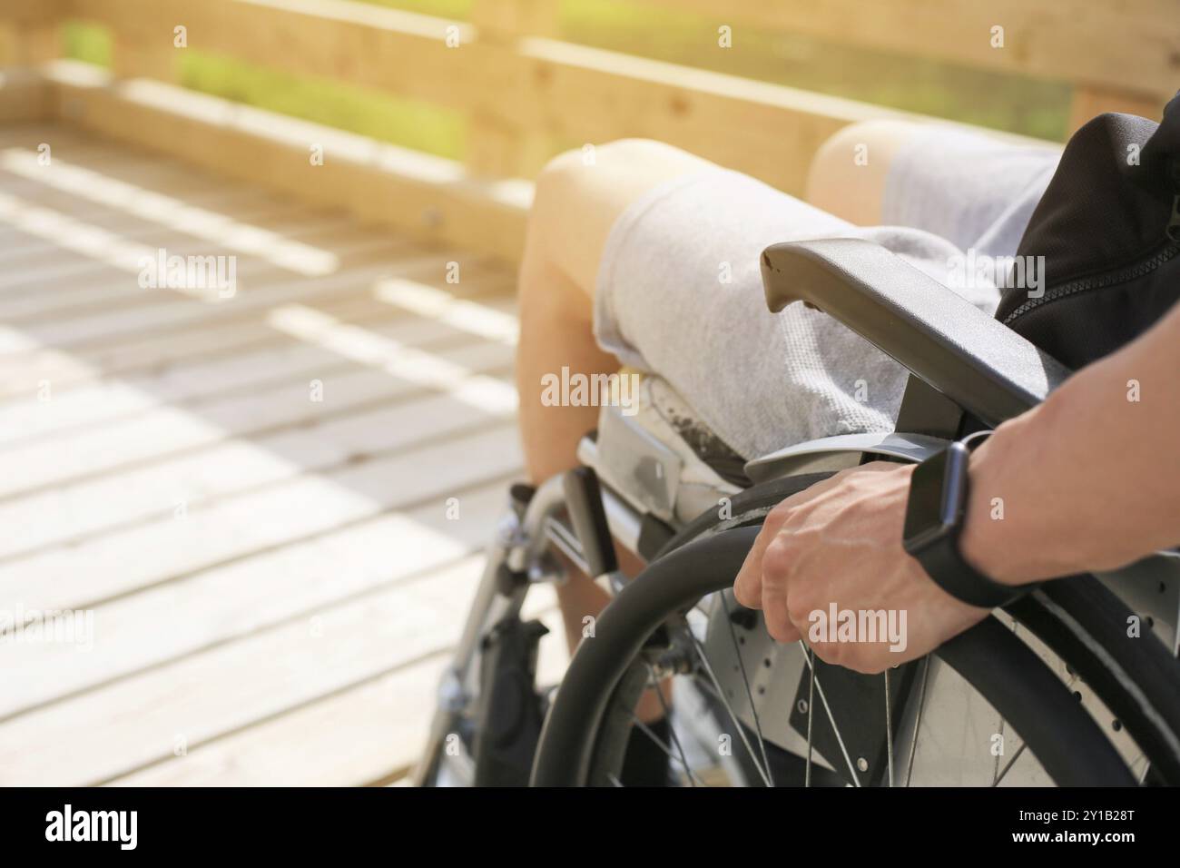 Disabled young athletic man on a wheelchair holding and turning wheels ...