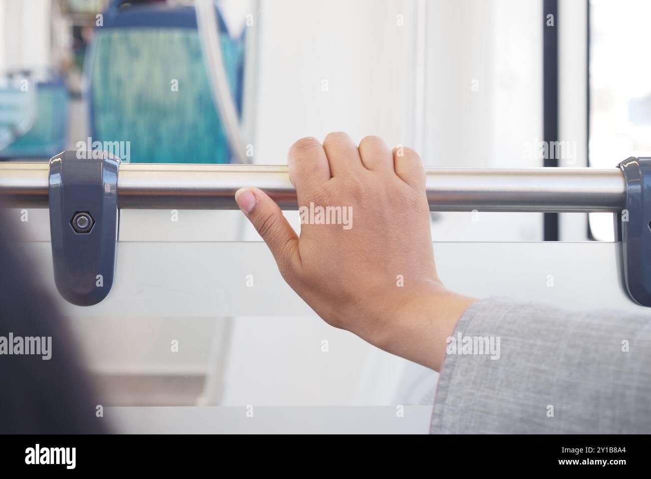 A hand gripping a rail in a public transportation setting, ensuring ...