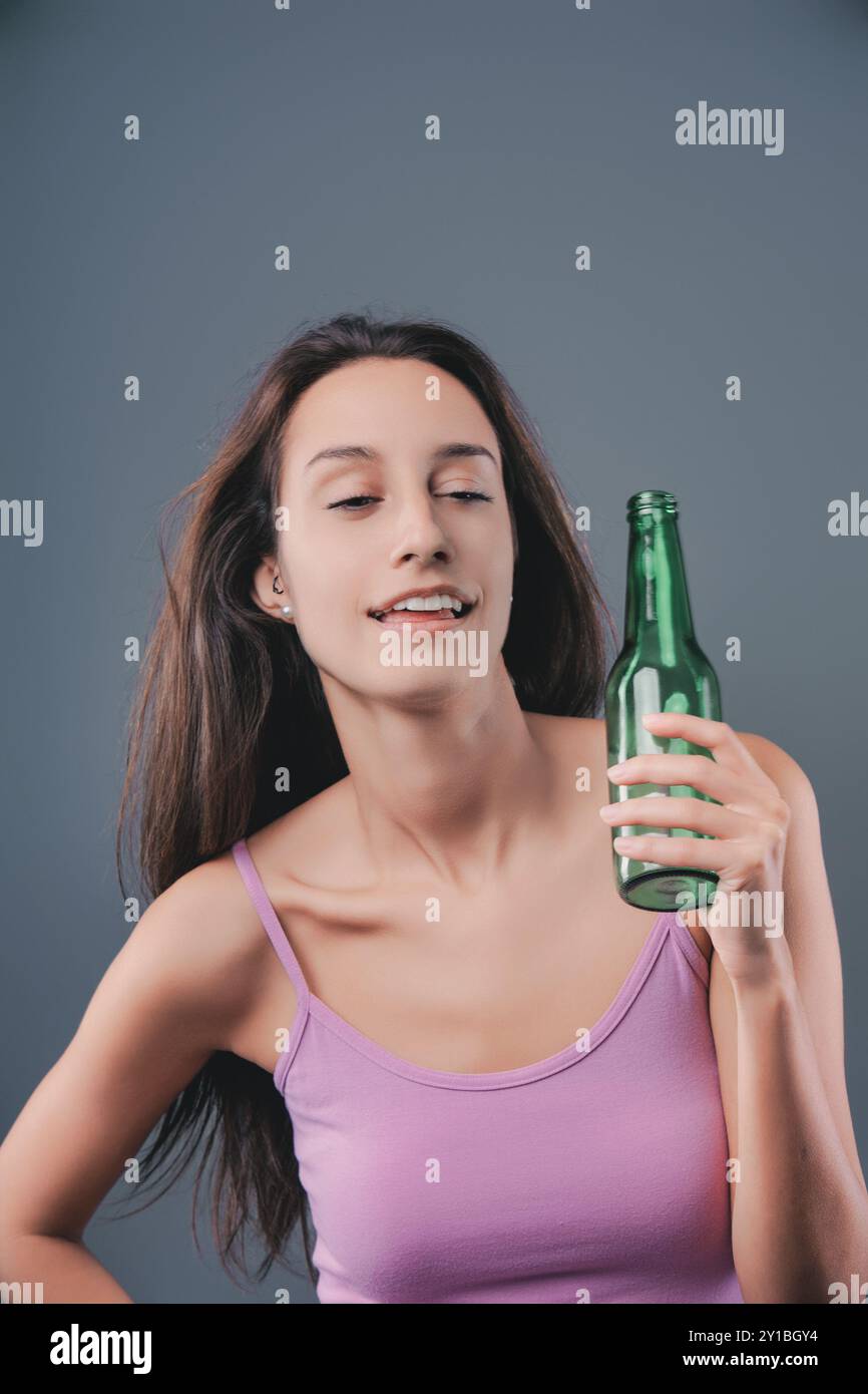 woman holds a green bottle loosely in her hand while her half-closed ...