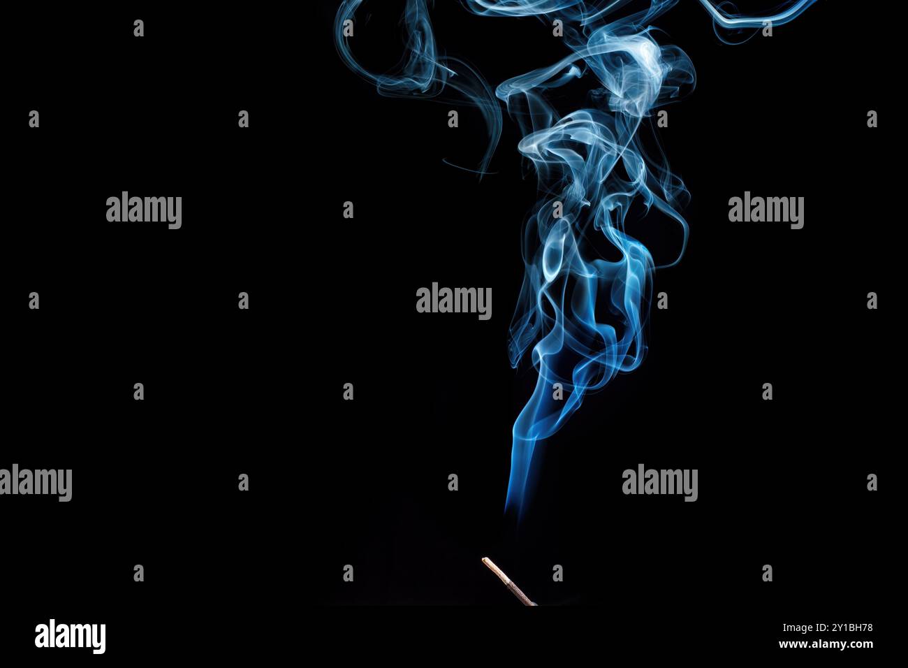 Vivid blue smoke wisp rising from a matchstick against a black ...