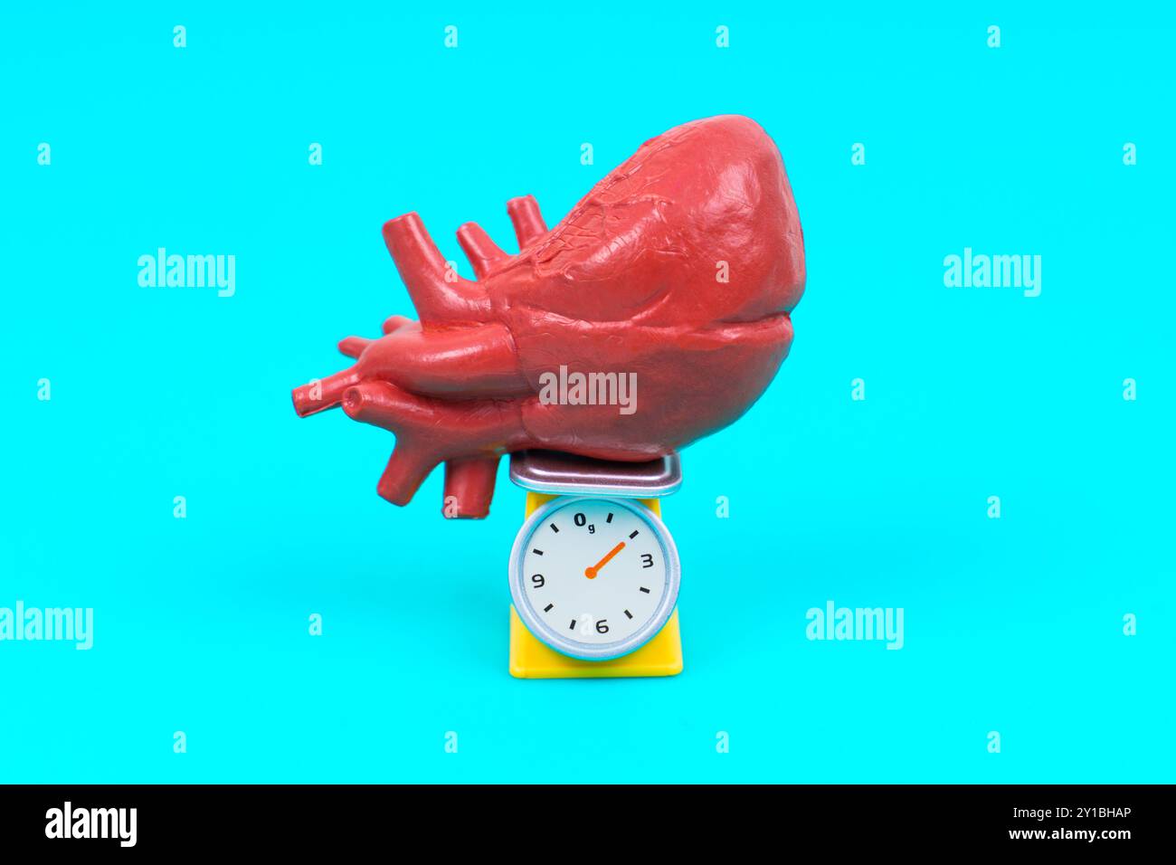Clay heart model balanced on a toy scale isolated on blue background ...