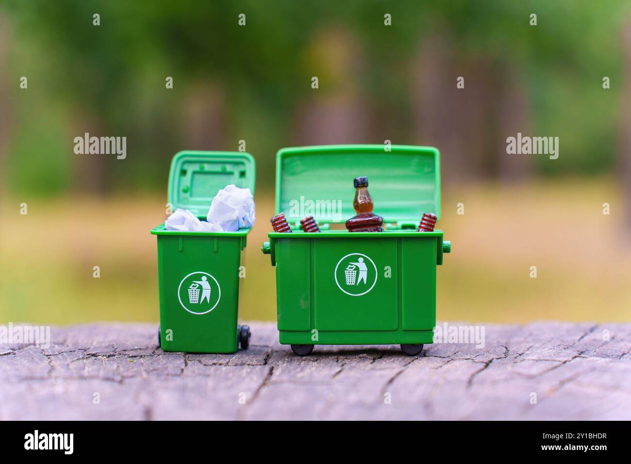 Two open miniature green trash bins filled with waste materials ...