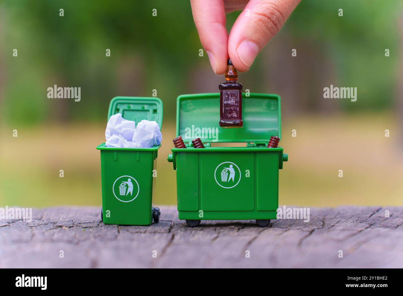 Close-up of a hand placing glass bottle into a miniature green ...