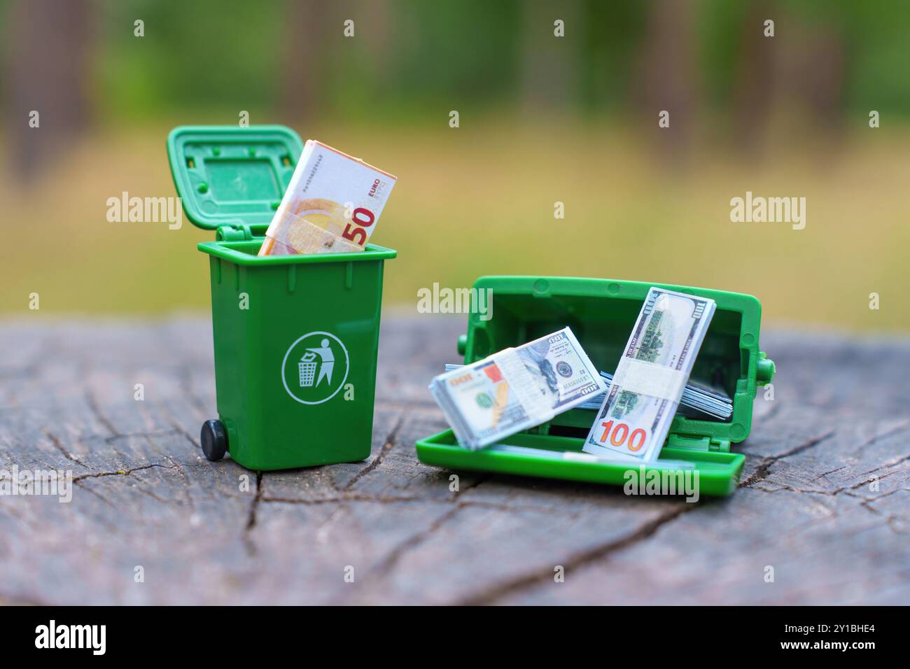 Two overflowing green trash bins filled with cash notes, representing ...