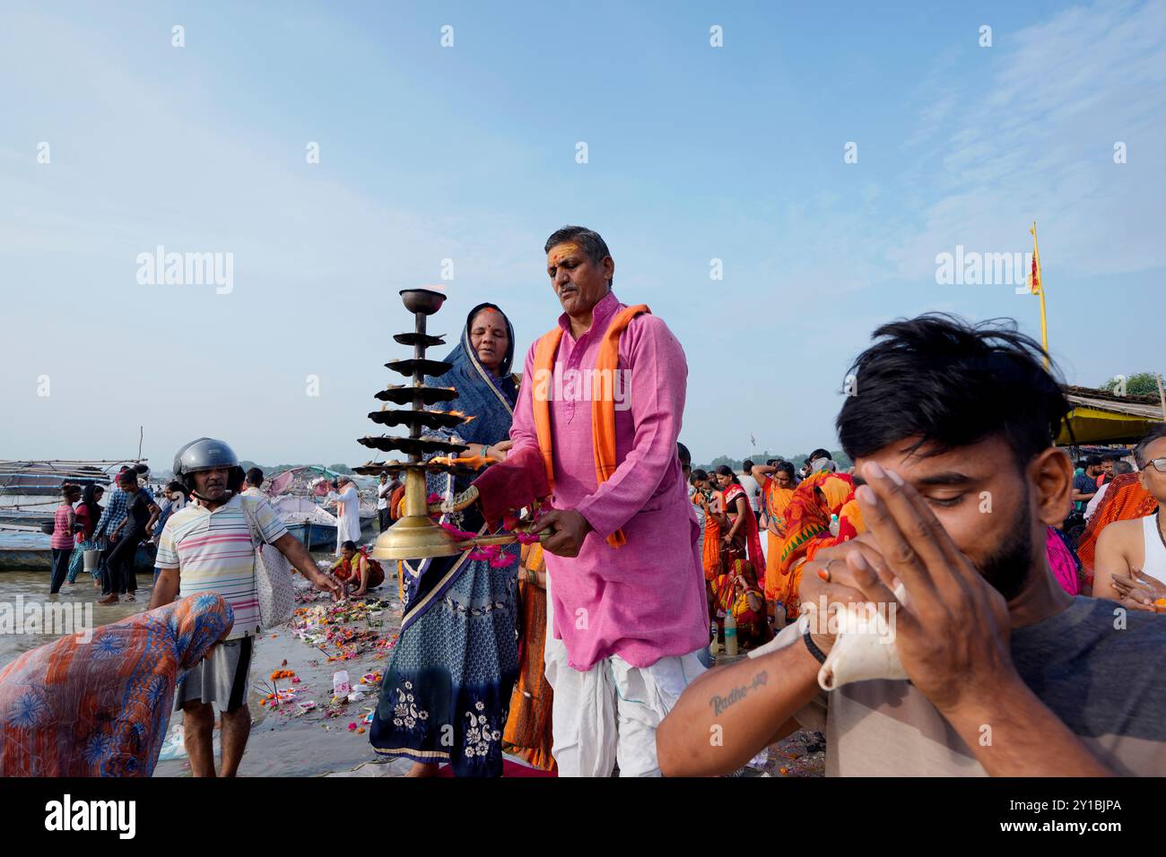A Hindu priest rotates traditional lamps in circular movement as he ...