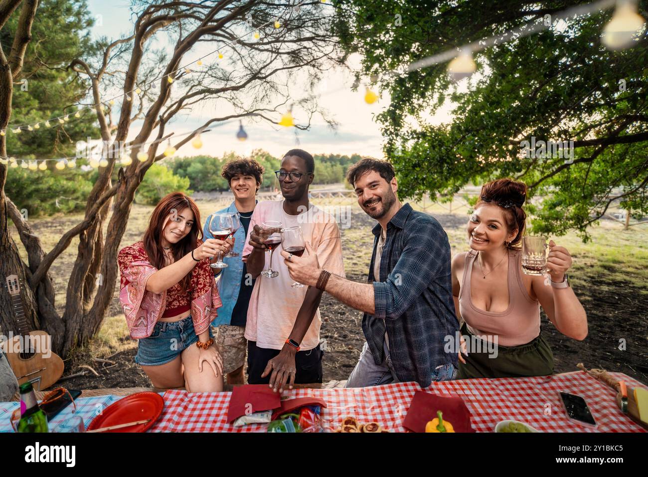Group of diverse young adults enjoying festive outdoor gathering ...