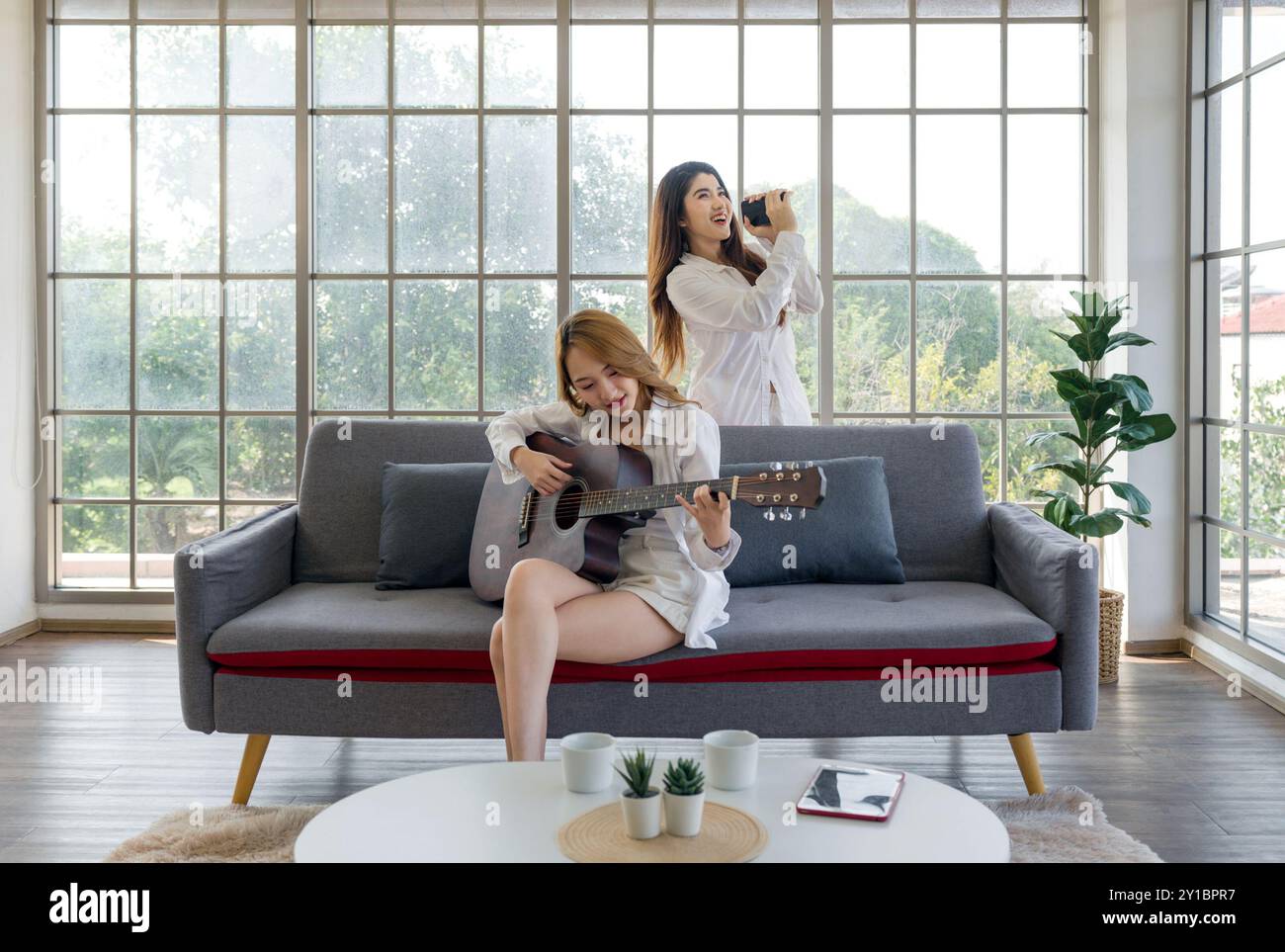Two women are enjoying themselves in a cozy living room. One playing ...