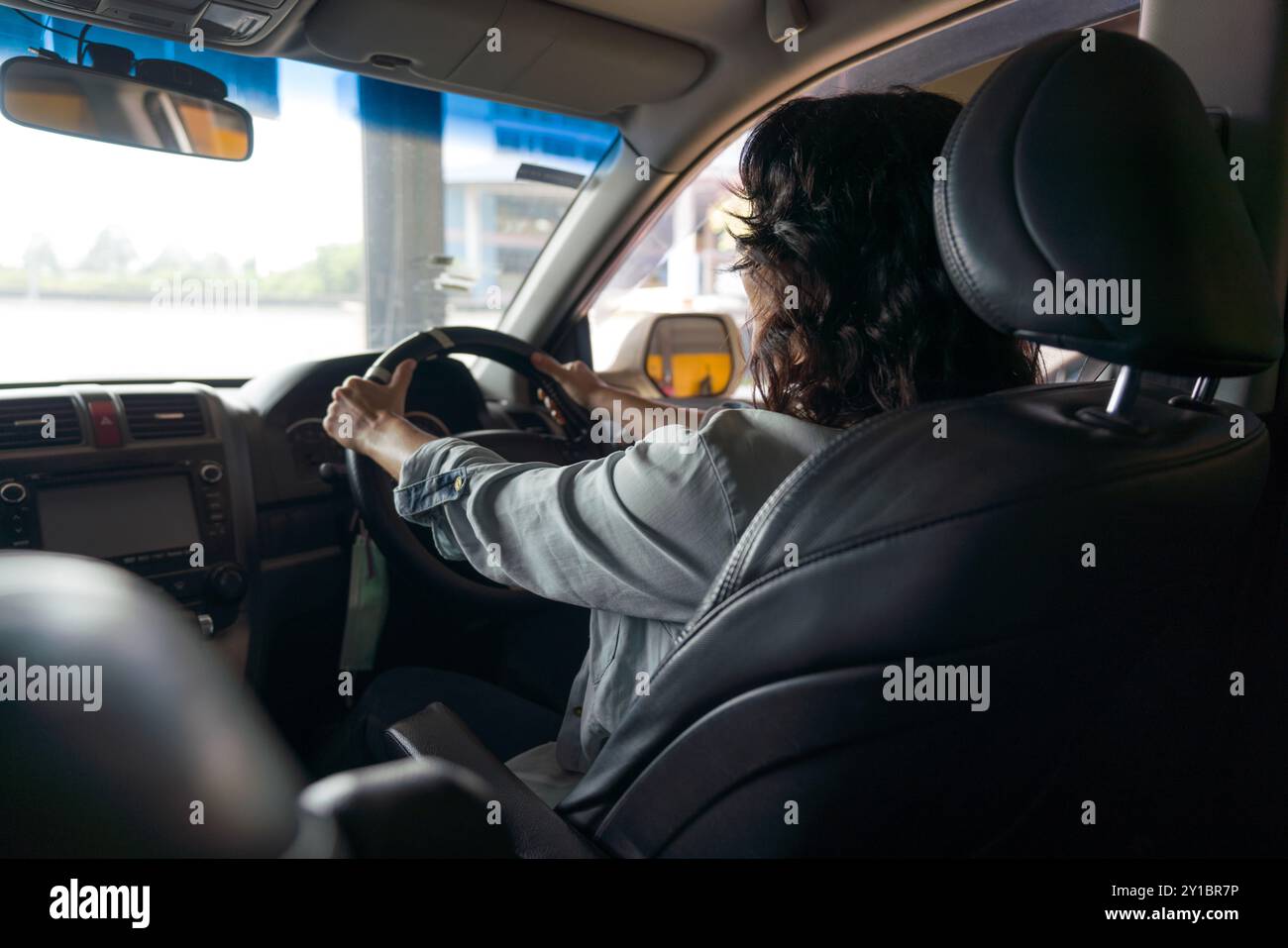 Woman driving out of a car repair shop. Driver hand holding steering ...