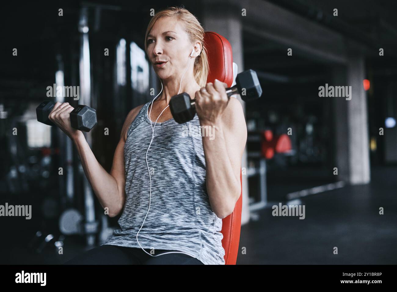 Weightlifting, earphones and mature woman in gym for workout, training ...