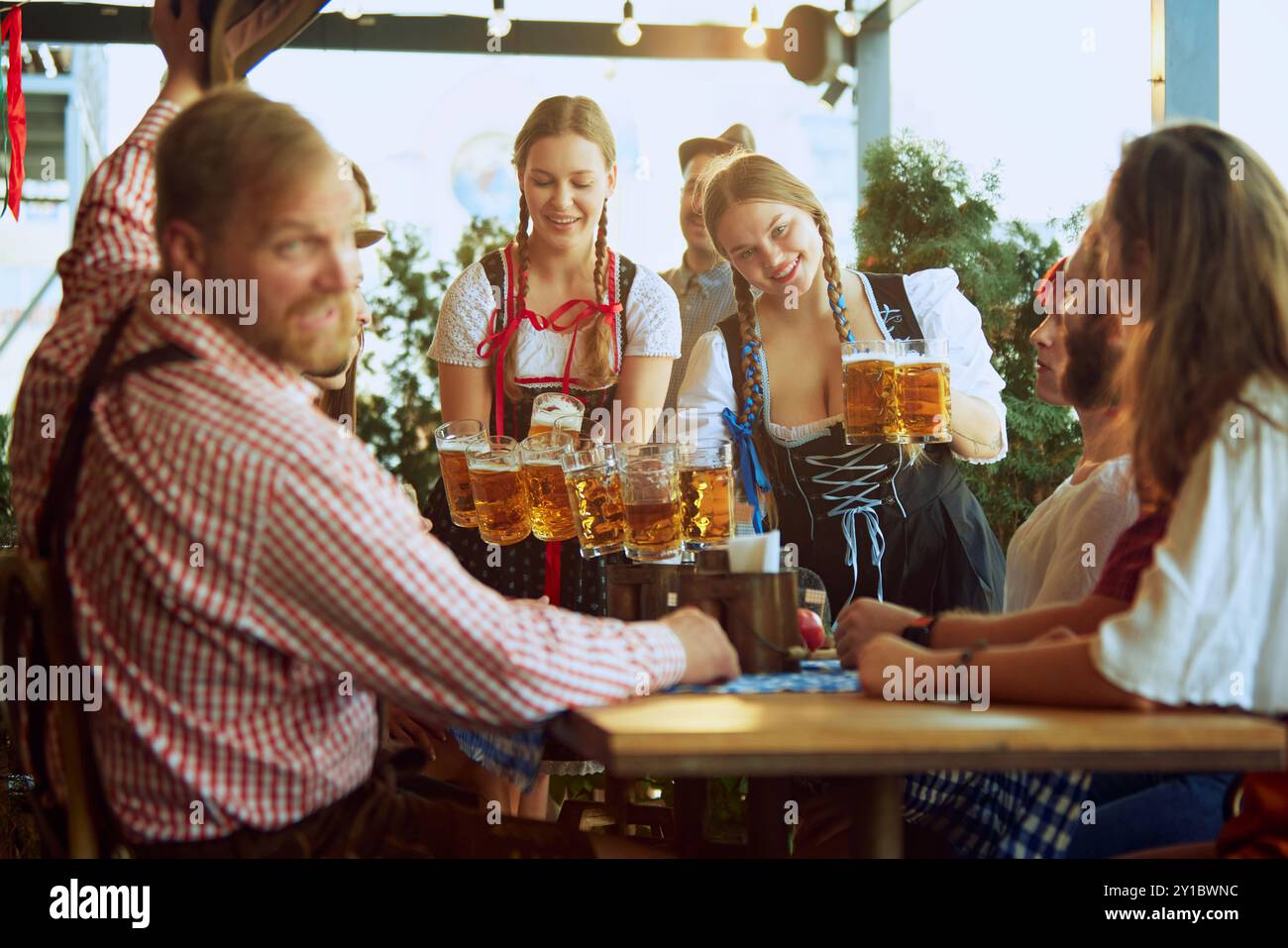 Two beautiful young women, waitress in traditional Bavarian clothes ...