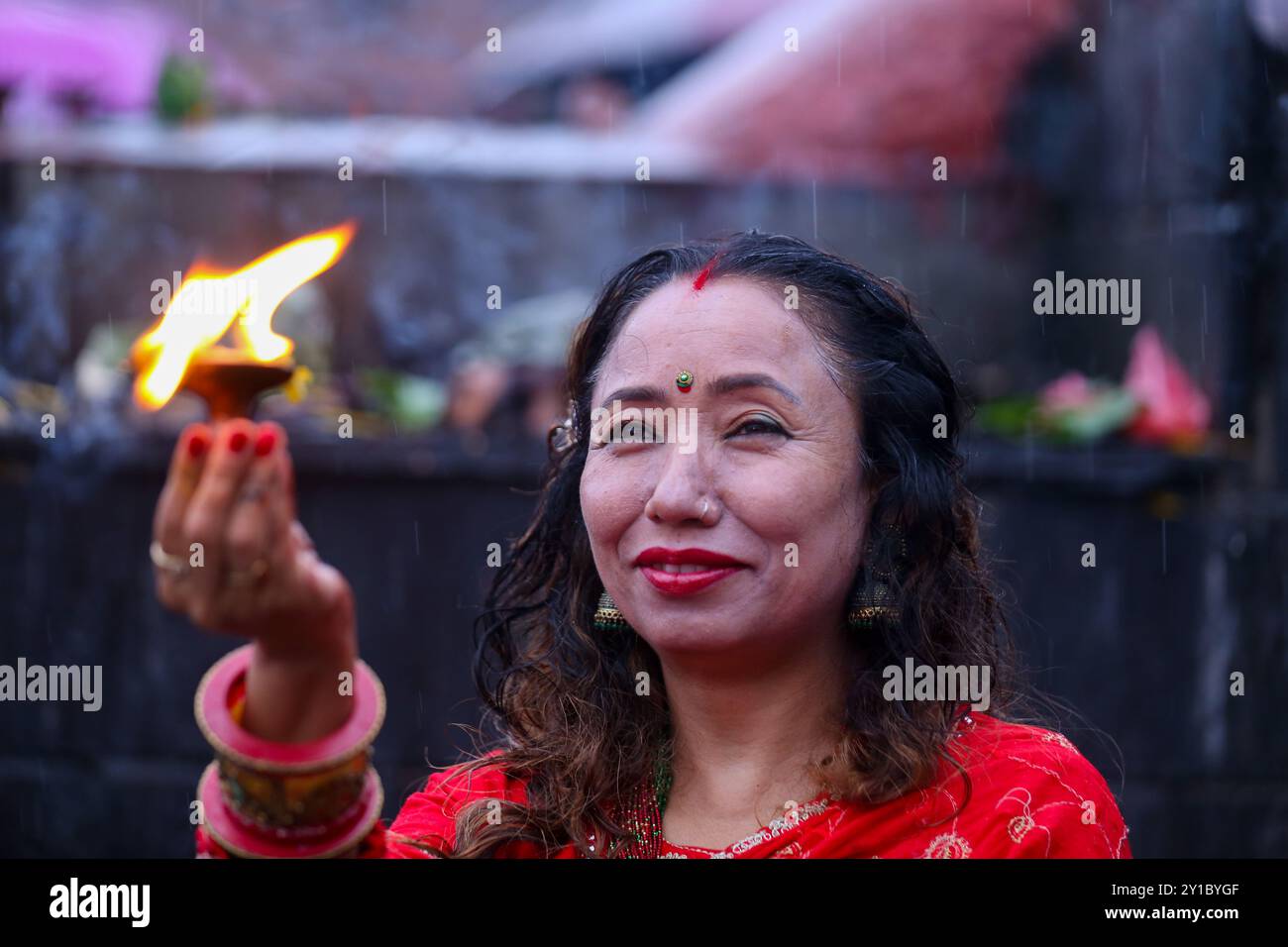 A fasting Nepali Hindu woman offers a butter-fed lamp while performing ...