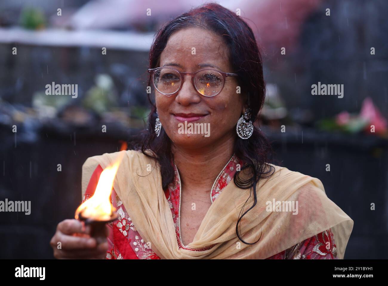 A fasting Nepali Hindu woman offers a butter-fed lamp while performing ...