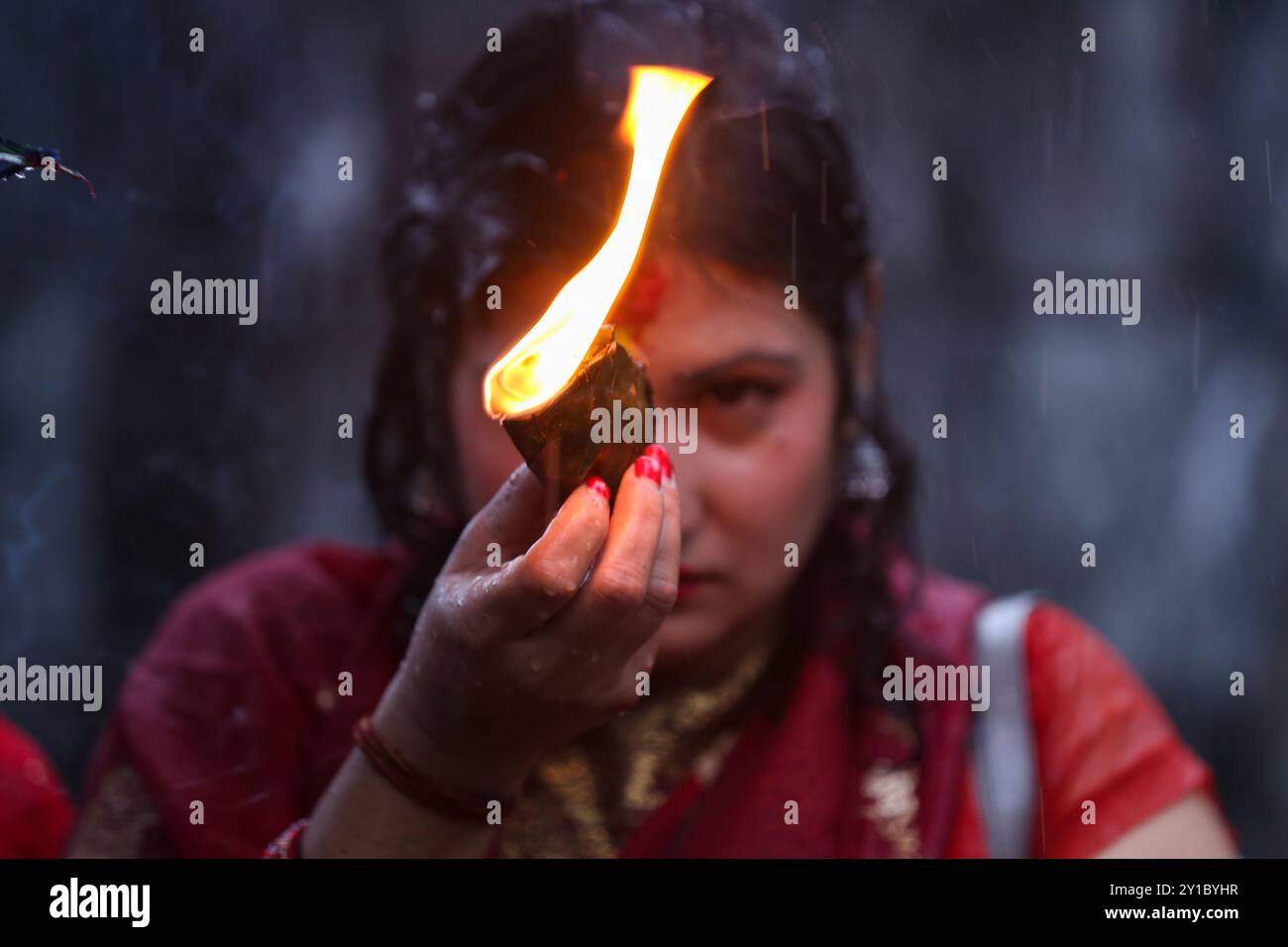A fasting Nepali Hindu woman offers a butter-fed lamp while performing ...