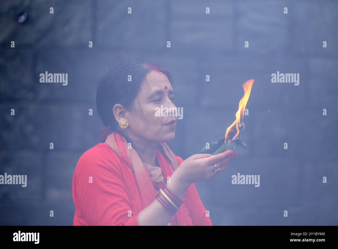 A fasting Nepali Hindu woman offers an oil-fed lamp while performing ...