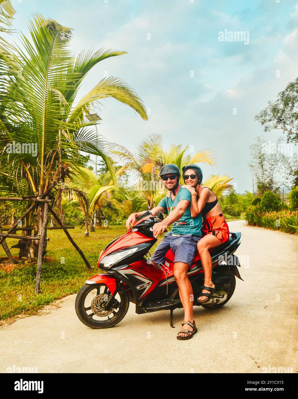 Happy smiling couple travelers riding motorbike scooter in safety ...
