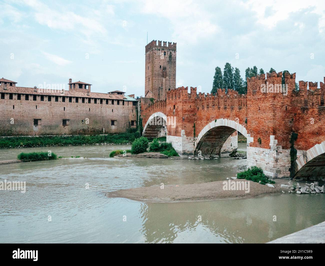 A medieval castle stands majestically next to a river, with an ...