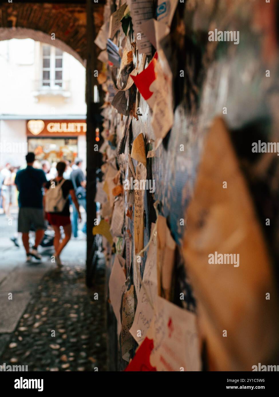 People stroll through a vibrant alley filled with handwritten notes and ...