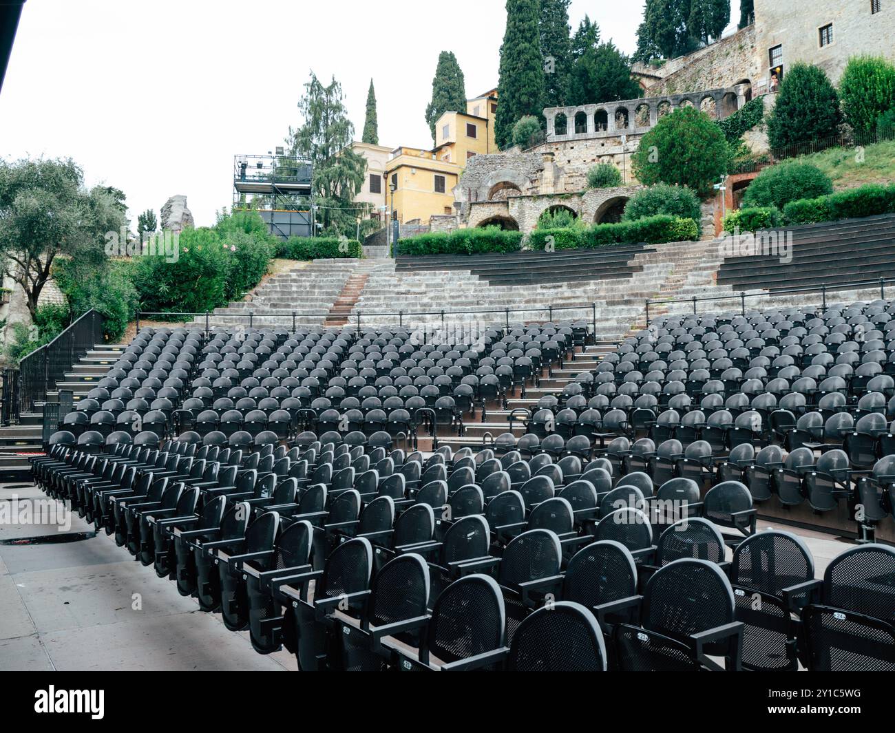 Rows of black seats fill an outdoor theater that overlooks lush ...