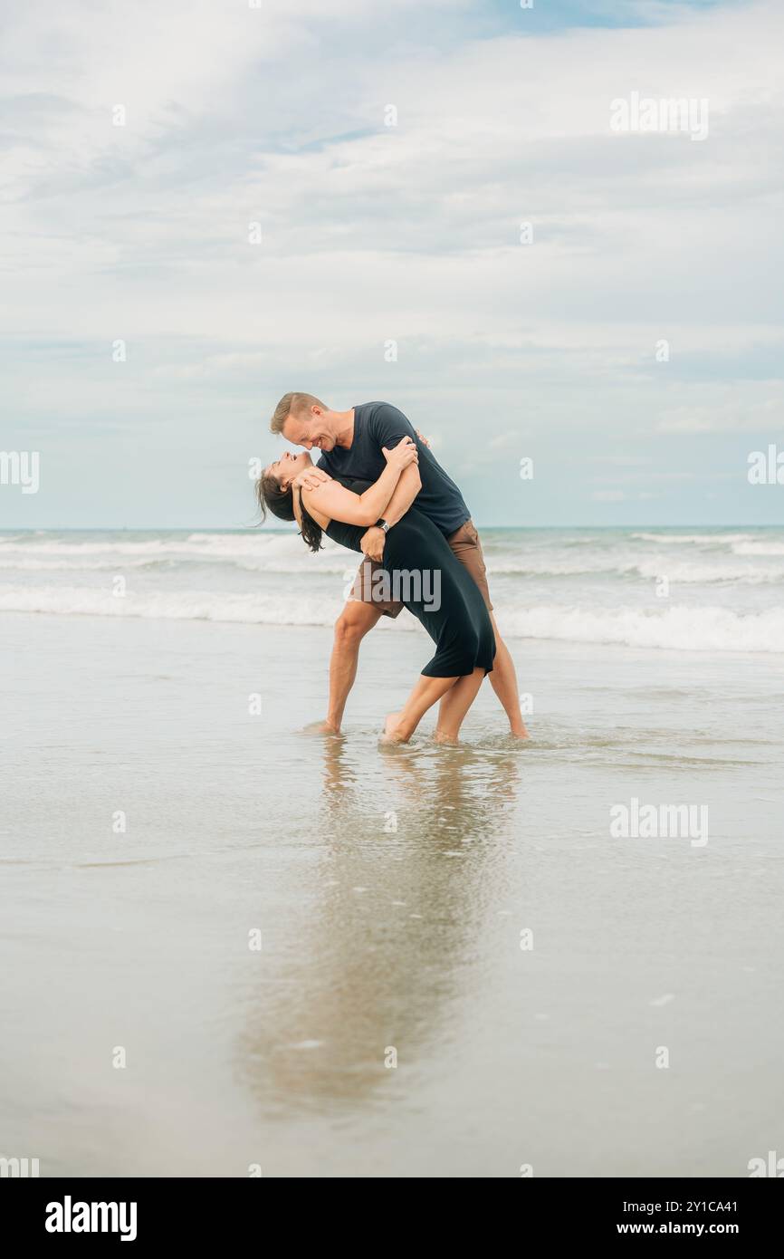 Couple dancing on the beach, man dipping woman as they smile Stock ...