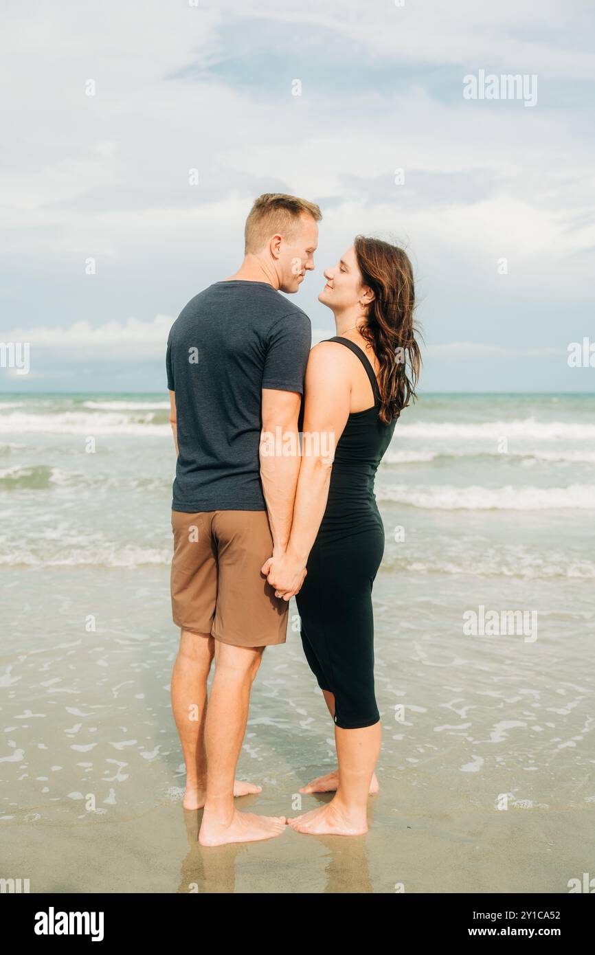 Couple standing on the beach, holding hands, facing each other Stock ...