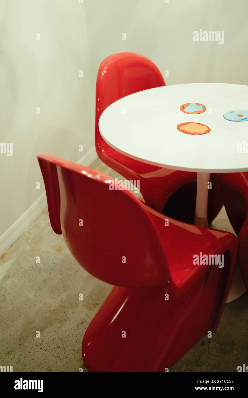 Modern red chairs around a white round table Stock Photo - Alamy