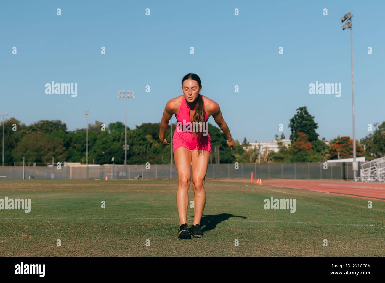 Female athlete performing hamstring sweeps during warm up Stock Photo ...
