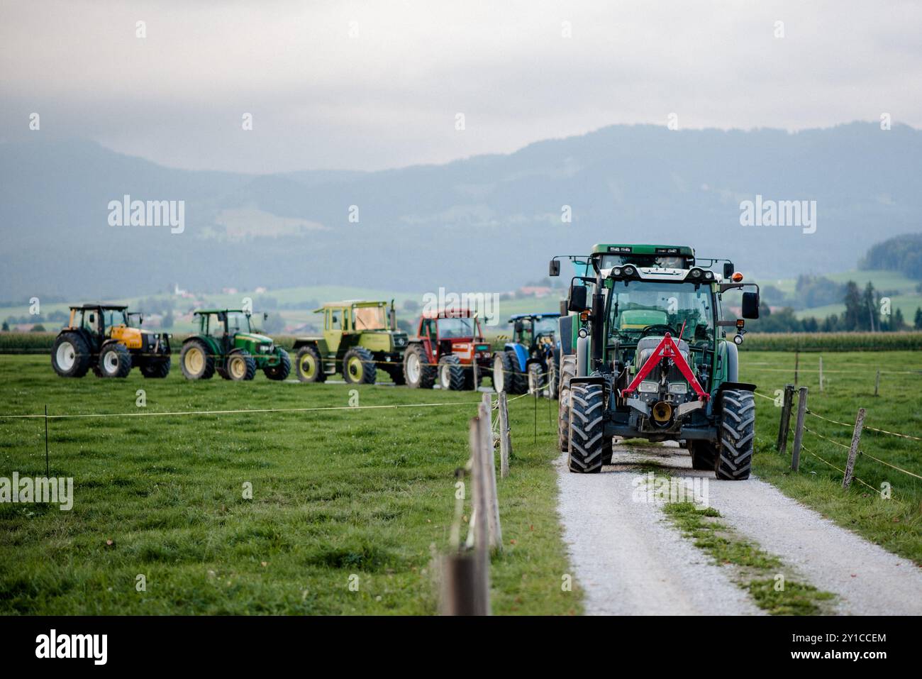 Line of tractors in Swiss farmland, with mountains in the background ...