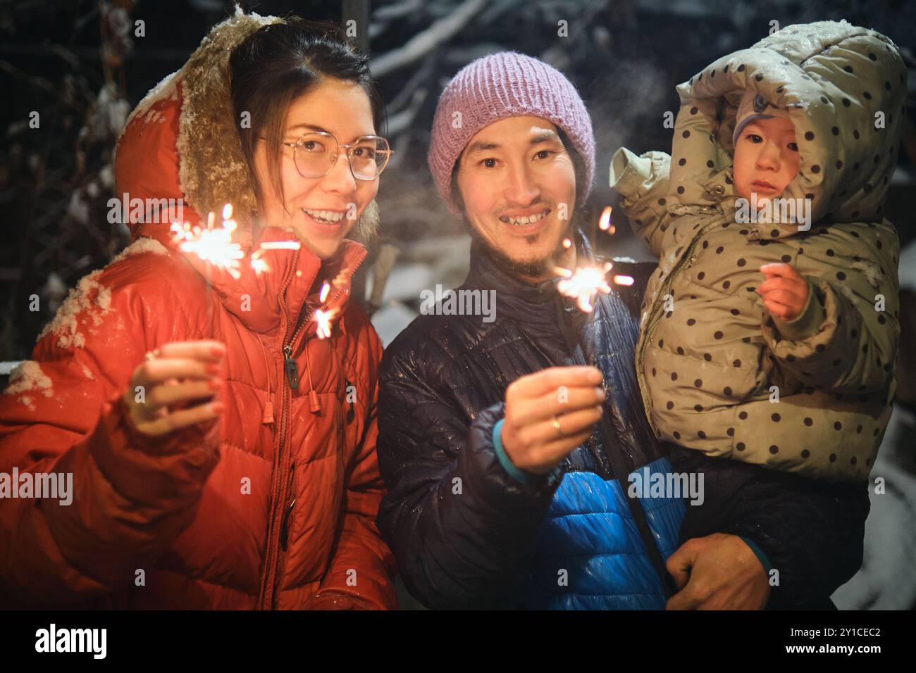 A family with a child celebrates the New Year together, burning Stock ...