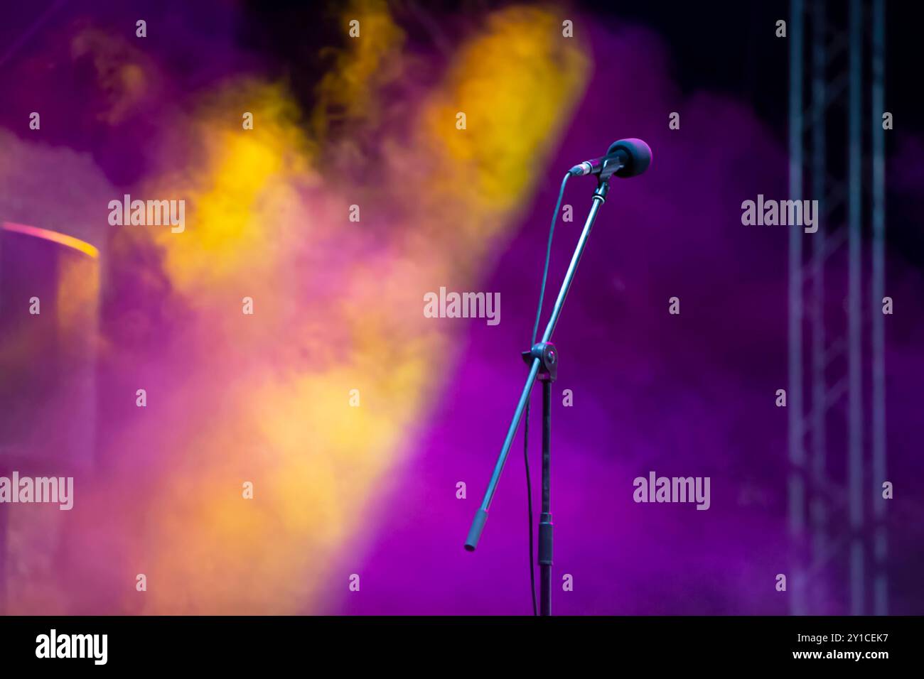 A stage microphone on a smoky purple background. The concert begins ...