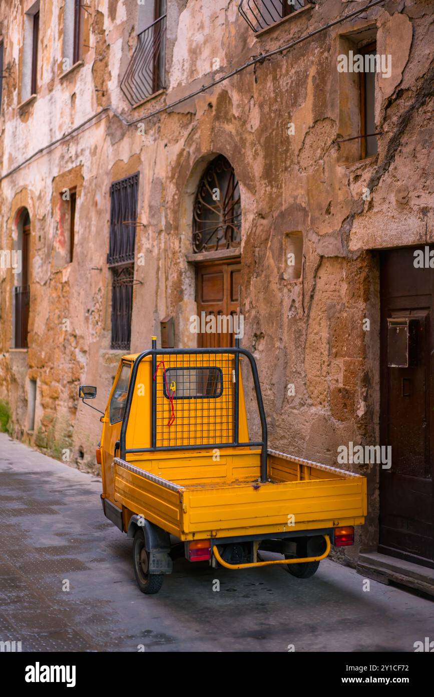 Iconic yellow Piaggio Ape three wheeler on an antique street of Italy ...