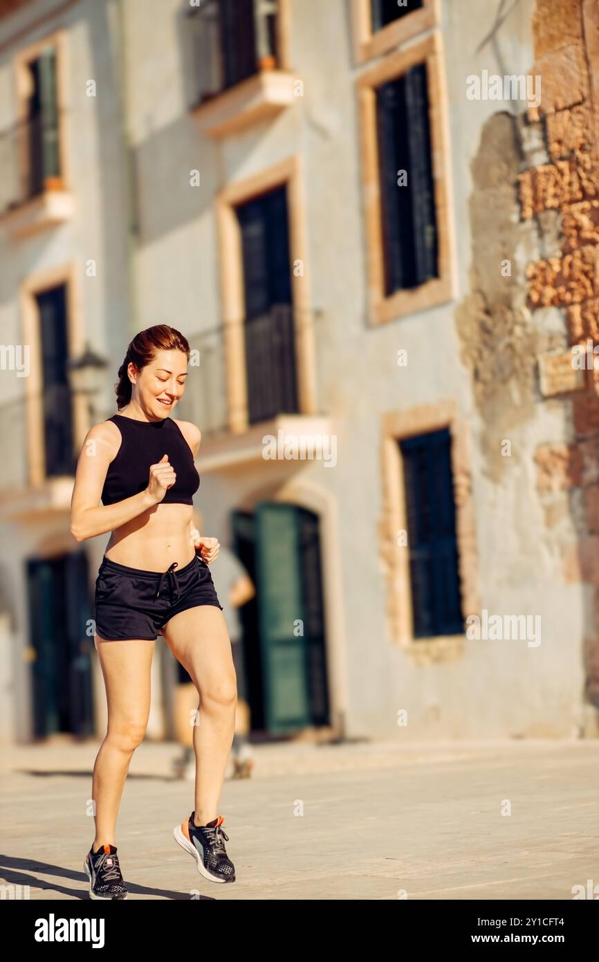 Athletic woman running past old city buildings Stock Photo - Alamy