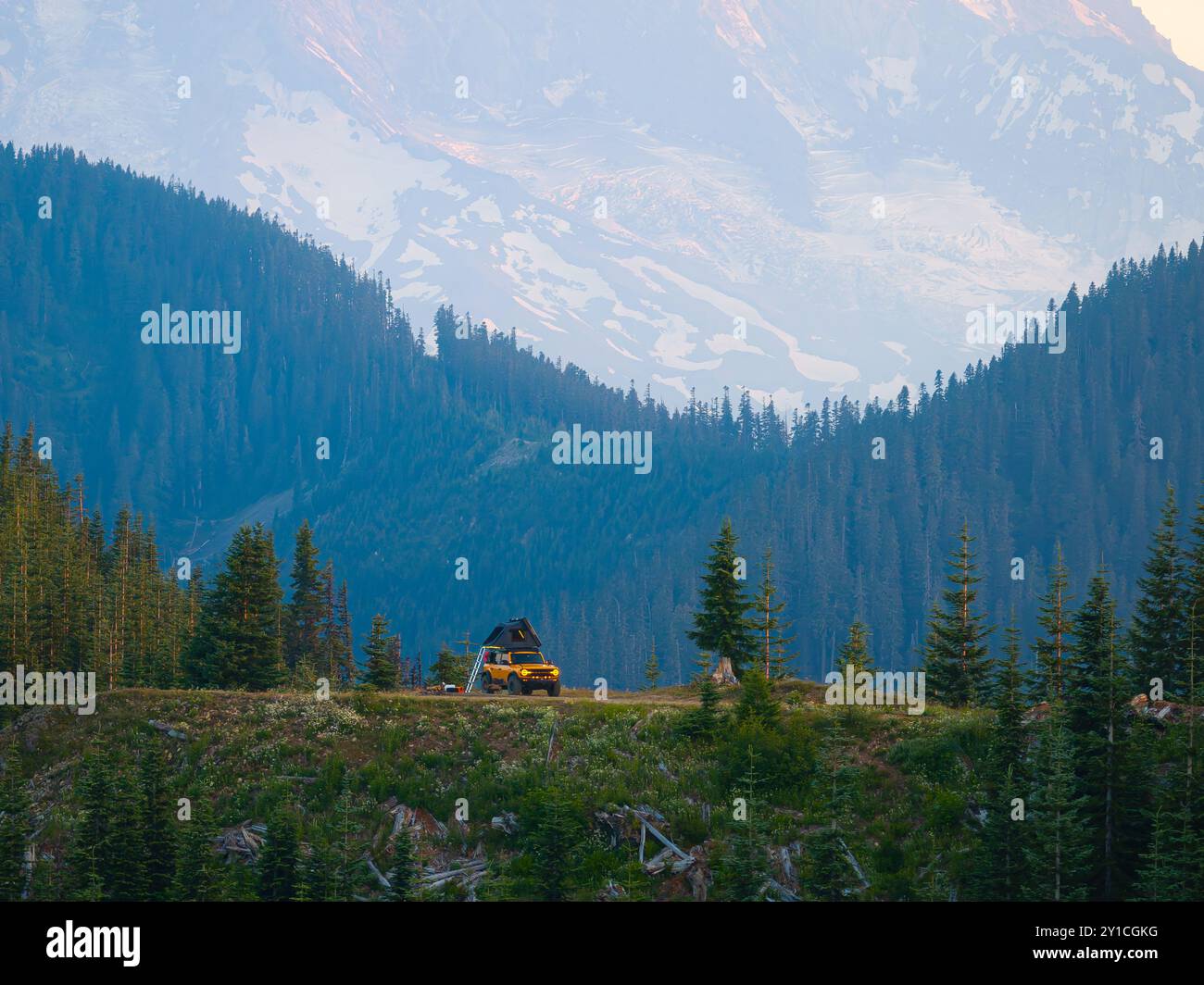 Yellow overlanding truck camping on cliff near Mt. Rainier, Washington ...